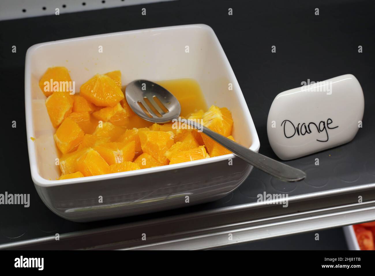 Fresh and delicious orange pieces in a bowl with a sign that says ...