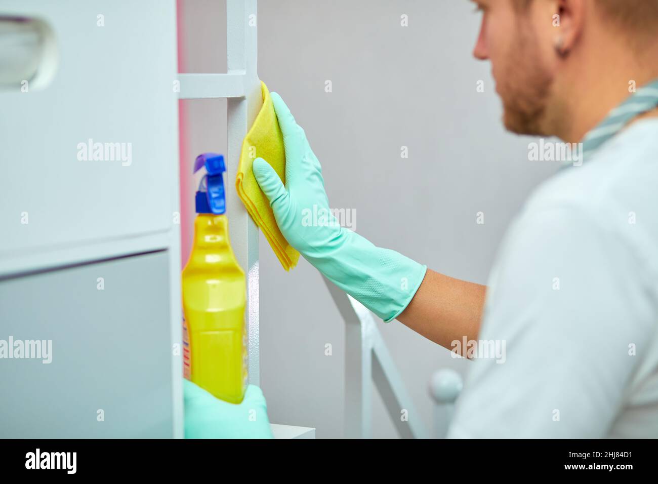 Bearded man cleaning home table surface with towel and gloves ...
