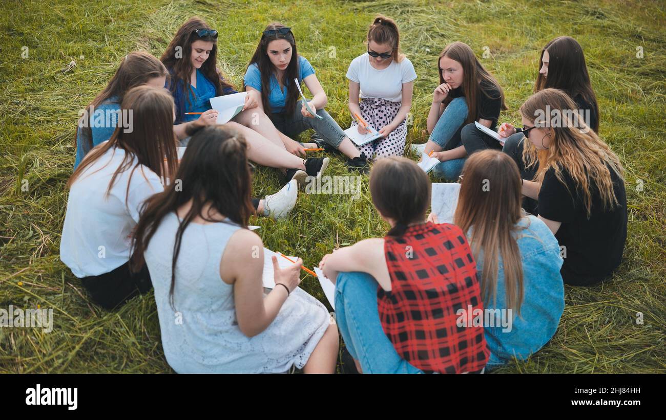 A group of female students are sitting in a circle on a meadow for ...