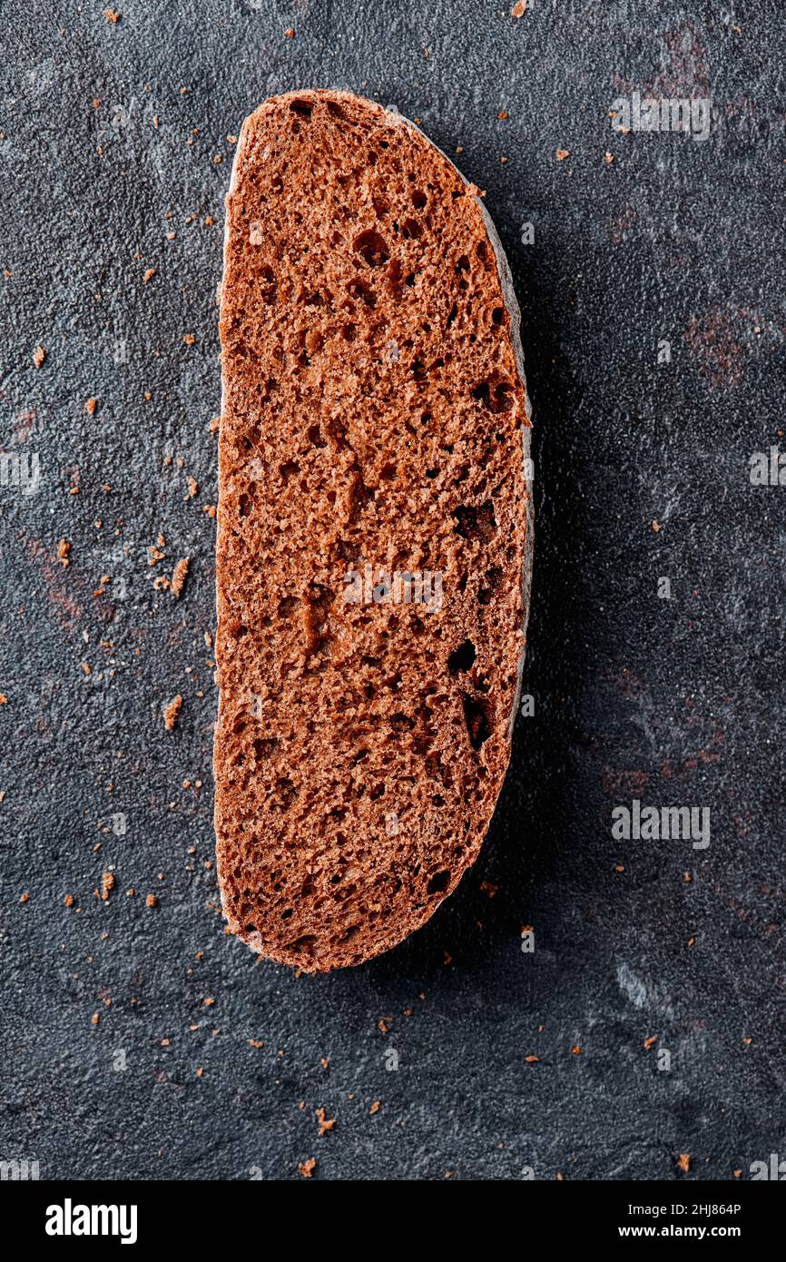 high angle view of a slice of rye bread on a black stone surface Stock ...