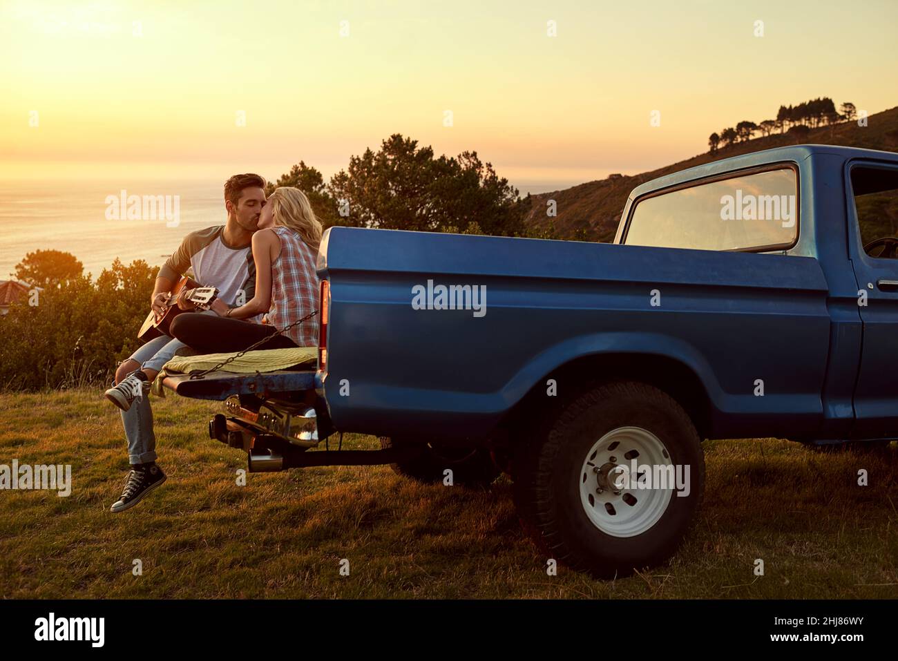 Making beautiful music together. Shot of a young man playing guitar for ...