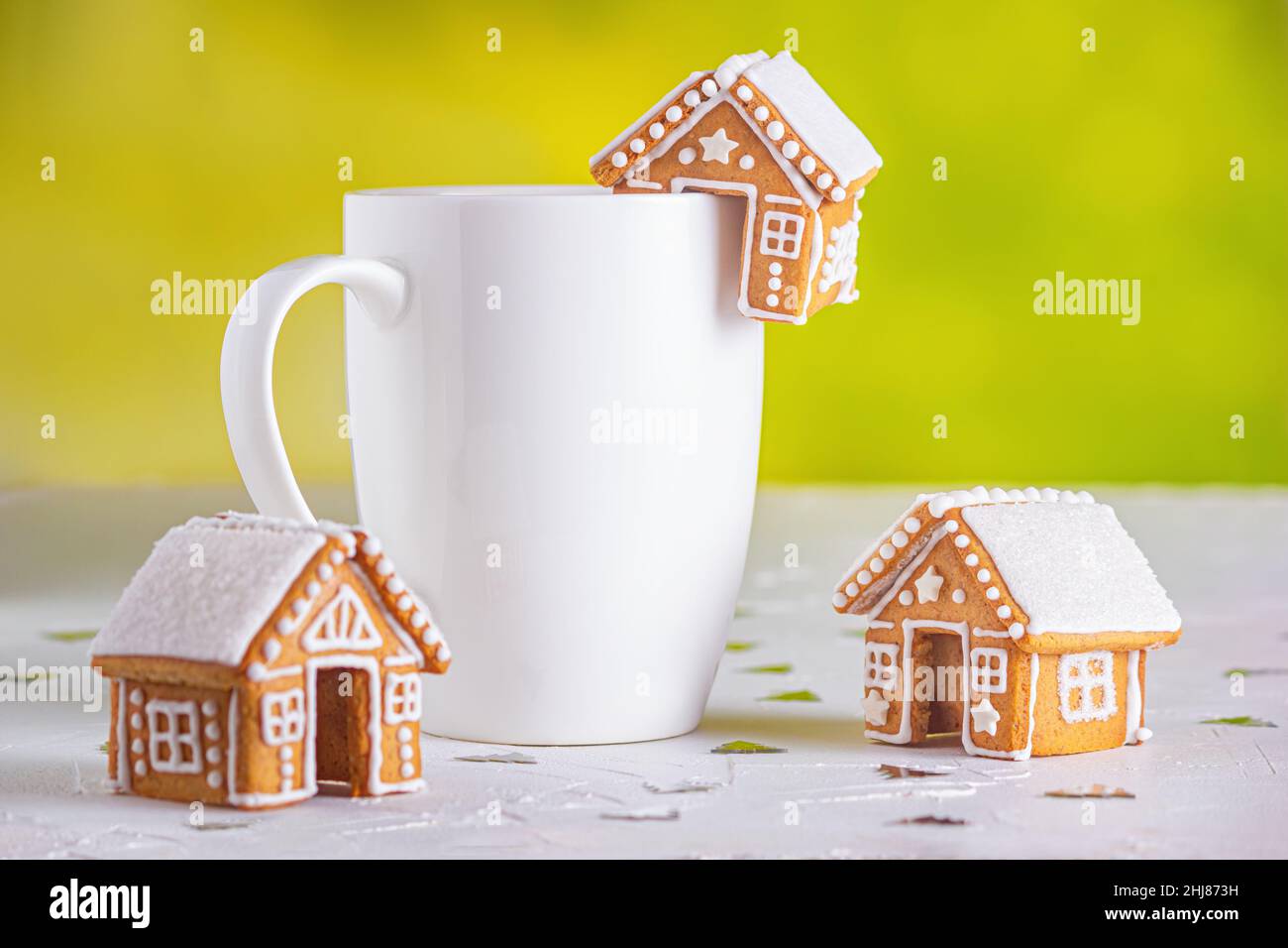 Gingerbread huts and a cup of milk on a white concrete surface with ...