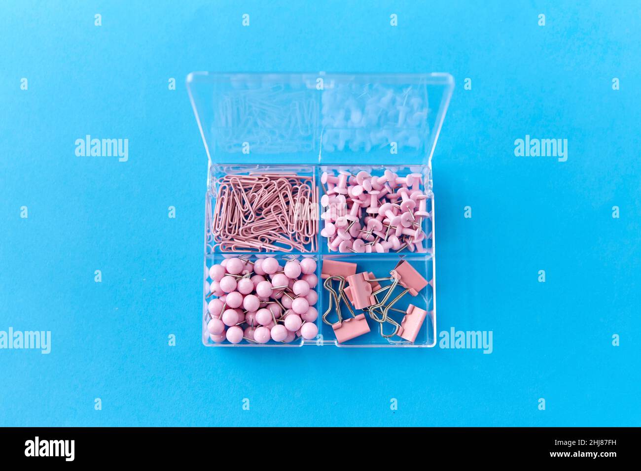 pins and clips in plastic pox on blue background Stock Photo - Alamy