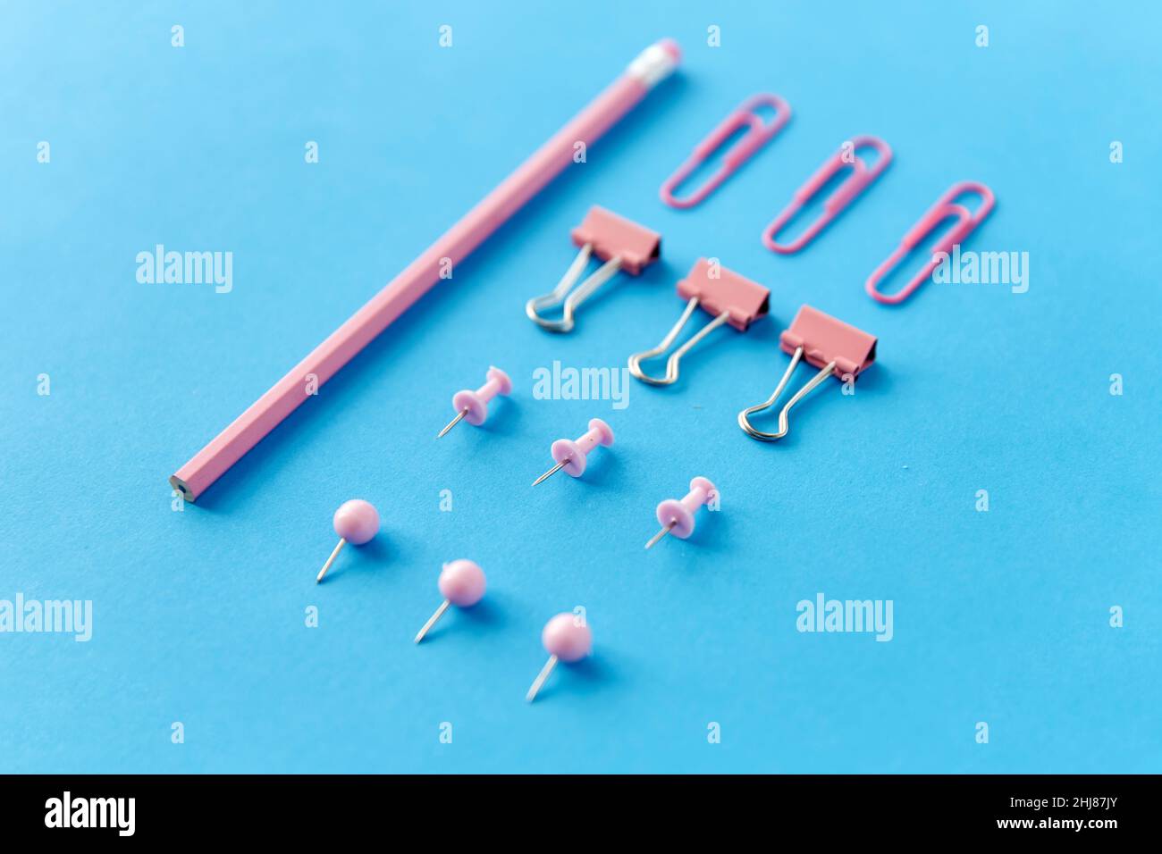 pink pencil, pins and clips on blue background Stock Photo - Alamy