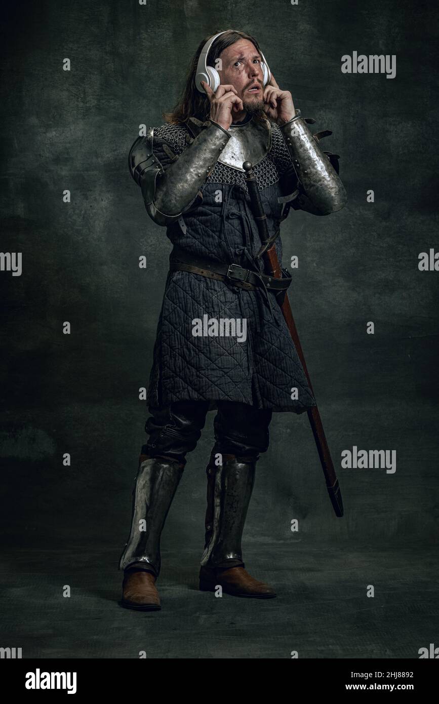 Young medieval warrior or knight with dirty wounded face in headphones ...