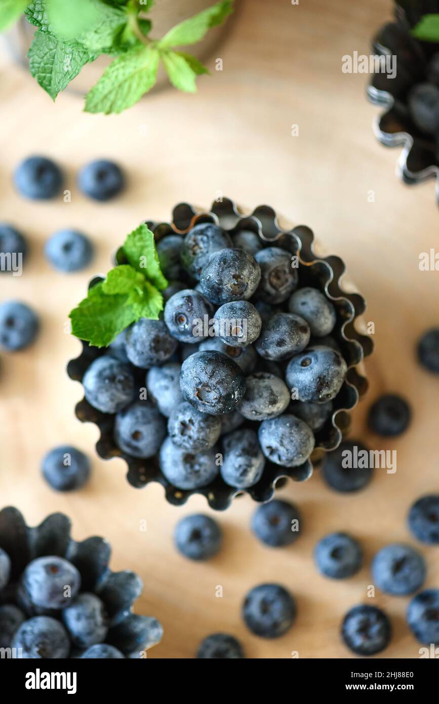 Juicy and fresh blueberries with green mint leaves on wooden table ...