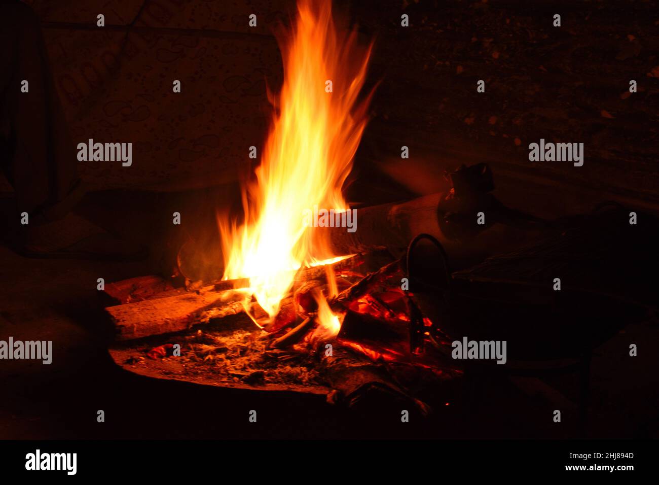 A bright camp fire with yellow and orange flames on a black dark ...