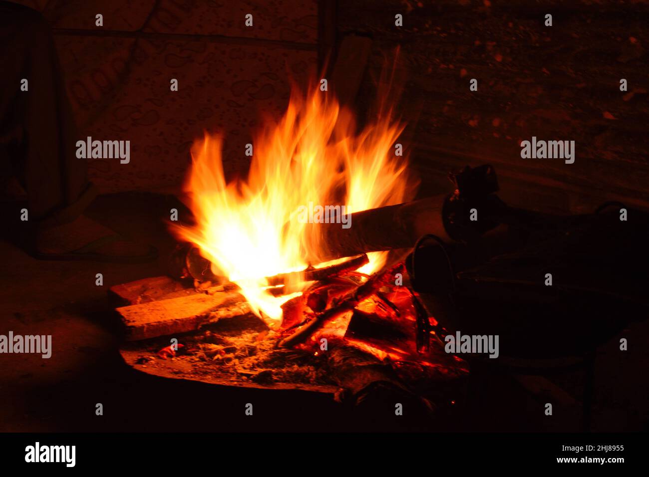 A bright camp fire with yellow and orange flames on a black dark ...