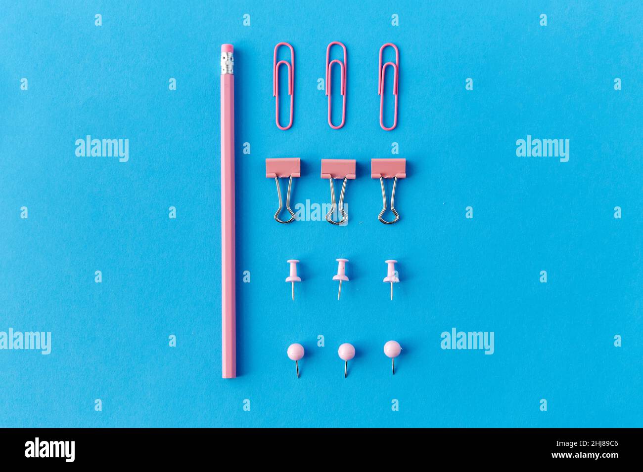 pink pencil, pins and clips on blue background Stock Photo - Alamy