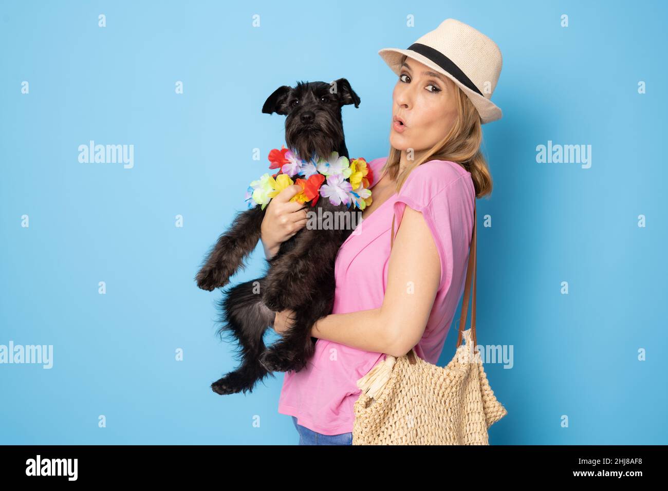 Positive female wearing straw hat with glad expression and her dog ...