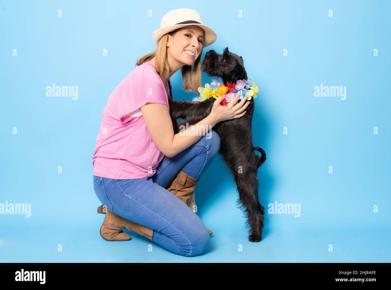 Positive female wearing straw hat with glad expression and her dog ...