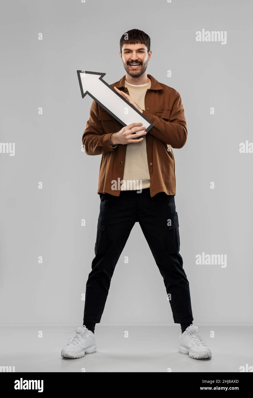 smiling young man holding big white arrow Stock Photo - Alamy