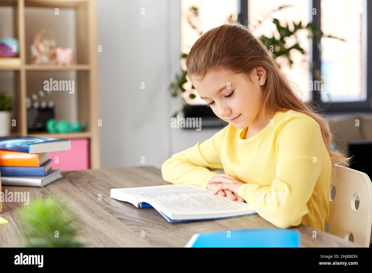 little student girl reading book at home Stock Photo - Alamy