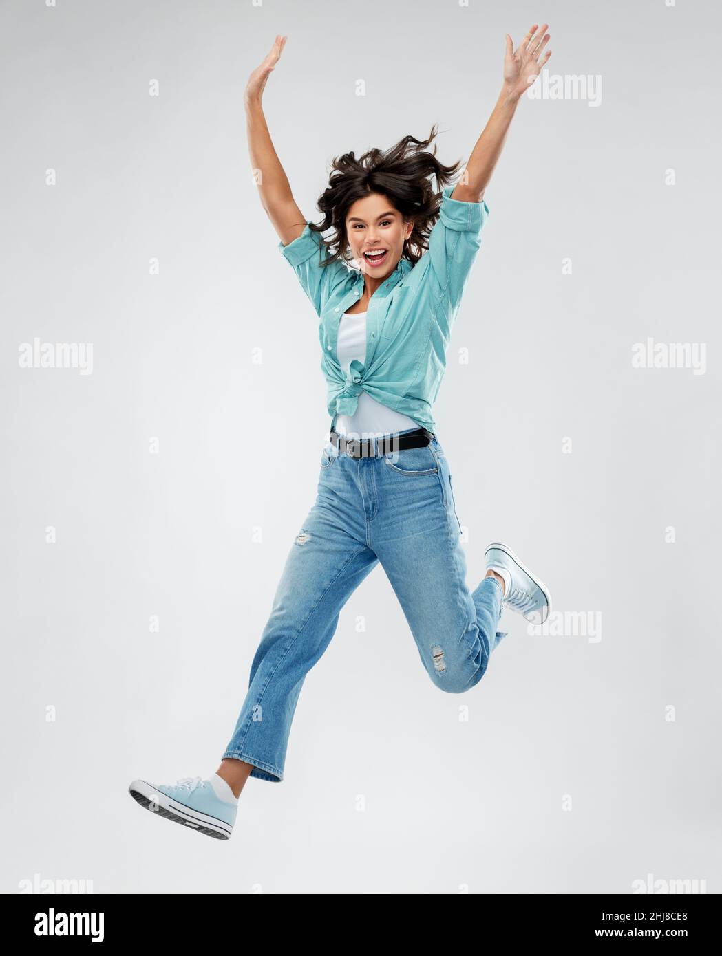 happy young woman jumping over grey background Stock Photo - Alamy