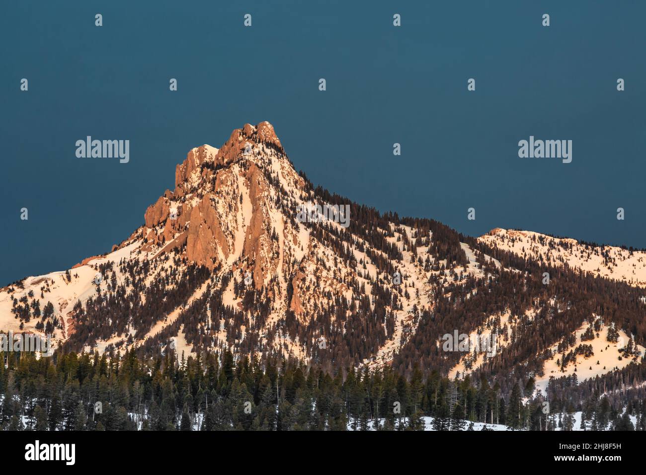 first light on ross peak in the bridger range against a dark winter sky ...