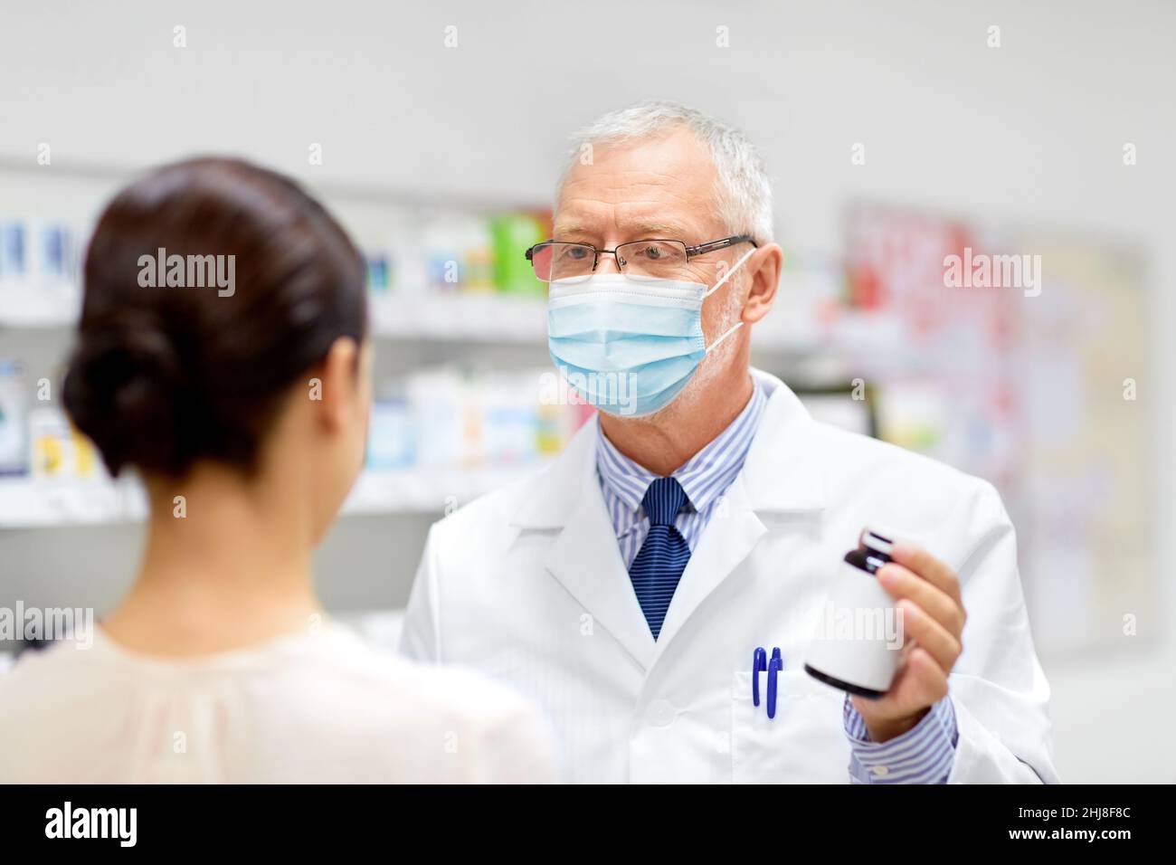 apothecary in mask showing drug to customer Stock Photo - Alamy