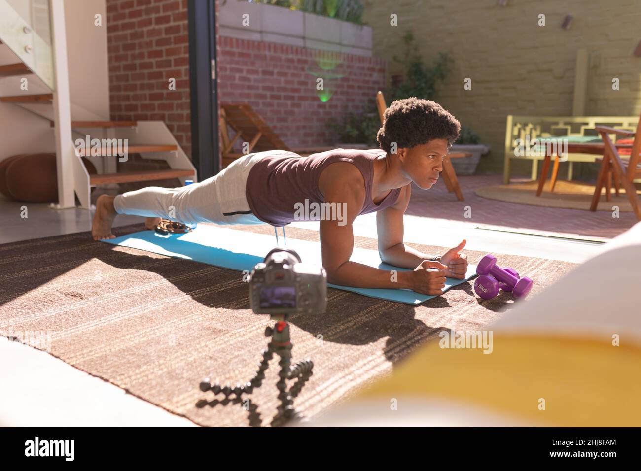African american young male influencer doing push-ups on exercise mat ...