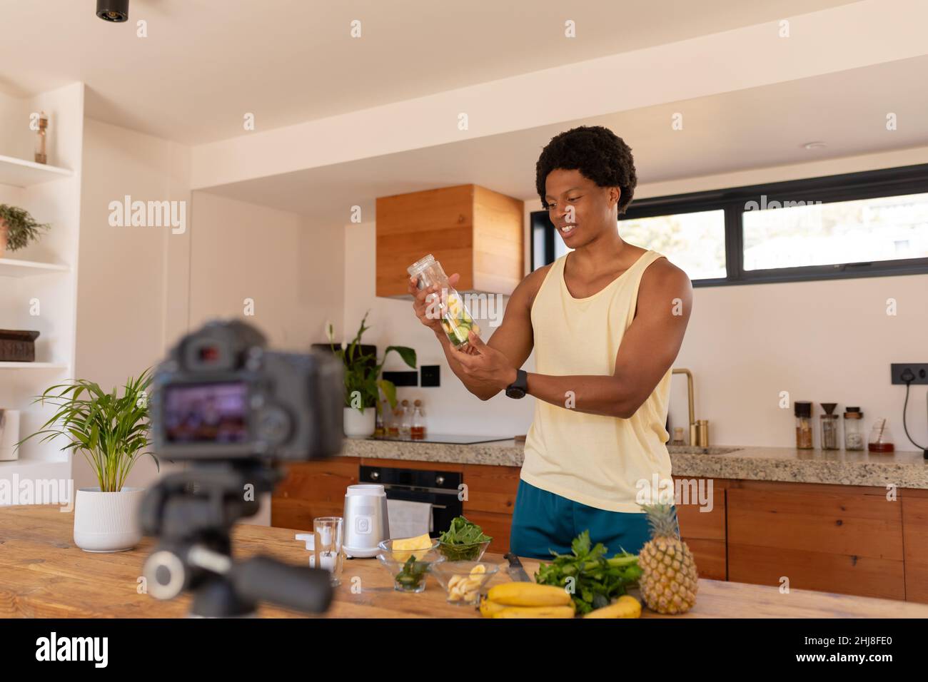 Smiling african american young male influencer preparing smoothie while ...