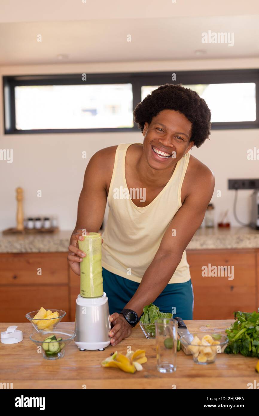 Portrait of smiling african american young man preparing smoothie in ...