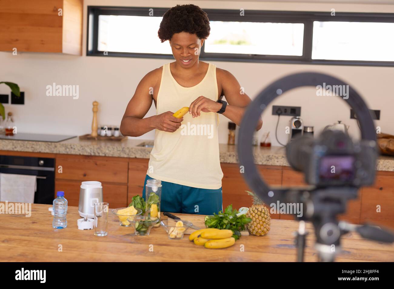 African american young male influencer peeling banana while making vlog ...