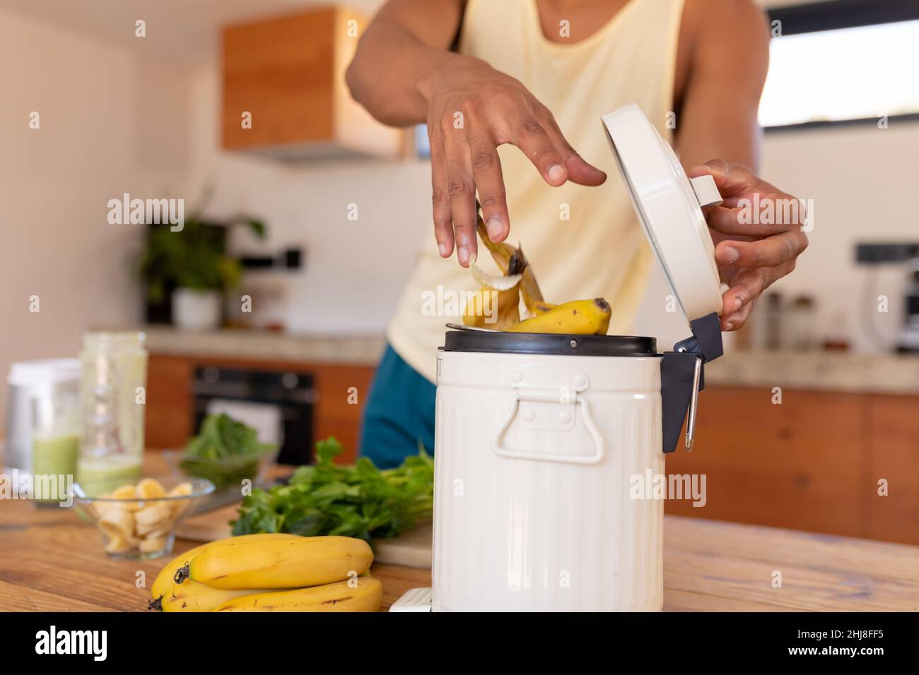 Midsection of african american young man throwing waste in garbage bin ...
