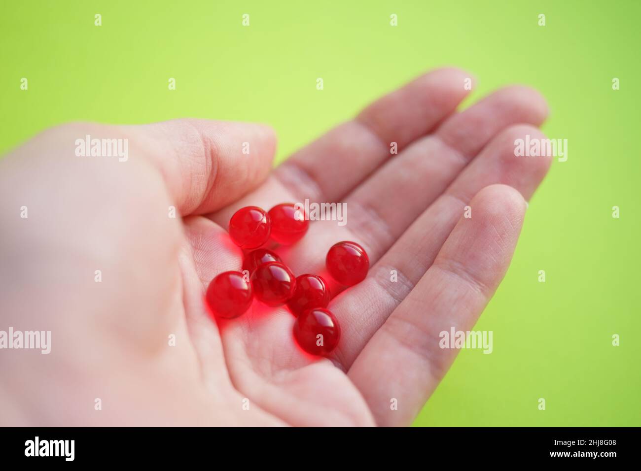 Round red vitamins in human palm. Vivid green background Stock Photo ...