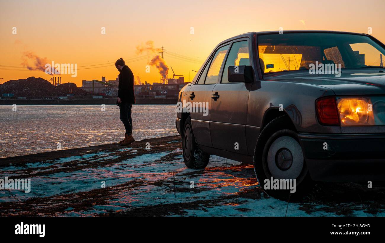 Person standing between car end waterfront durring sunset Stock Photo ...
