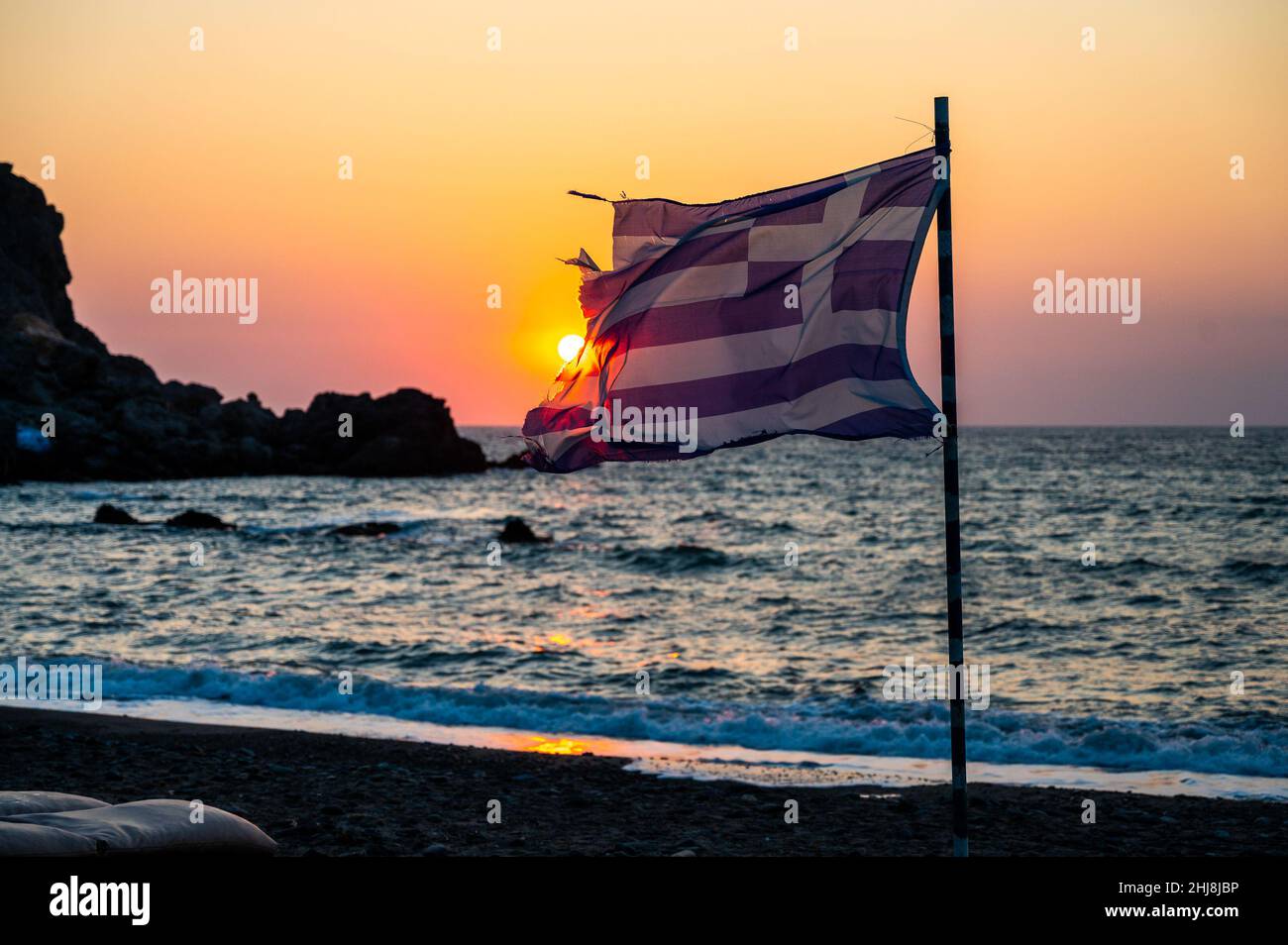 Greek flag waving at sunset on a sandy beach in Crete, Greece. Idyllic ...