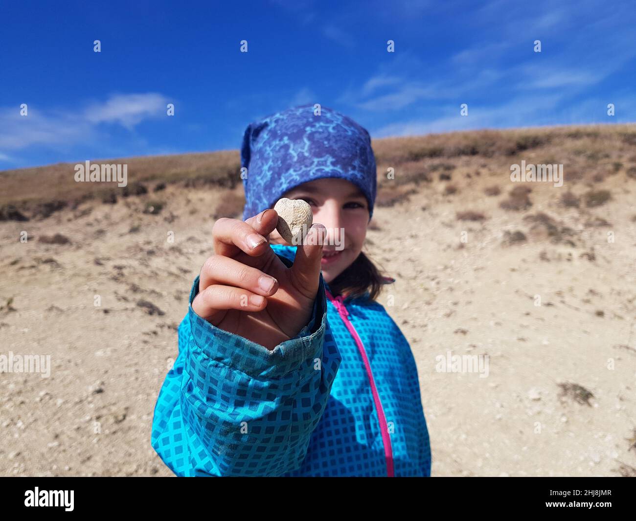 Portrait of child girl holding in her hand and showing a fossil shell ...