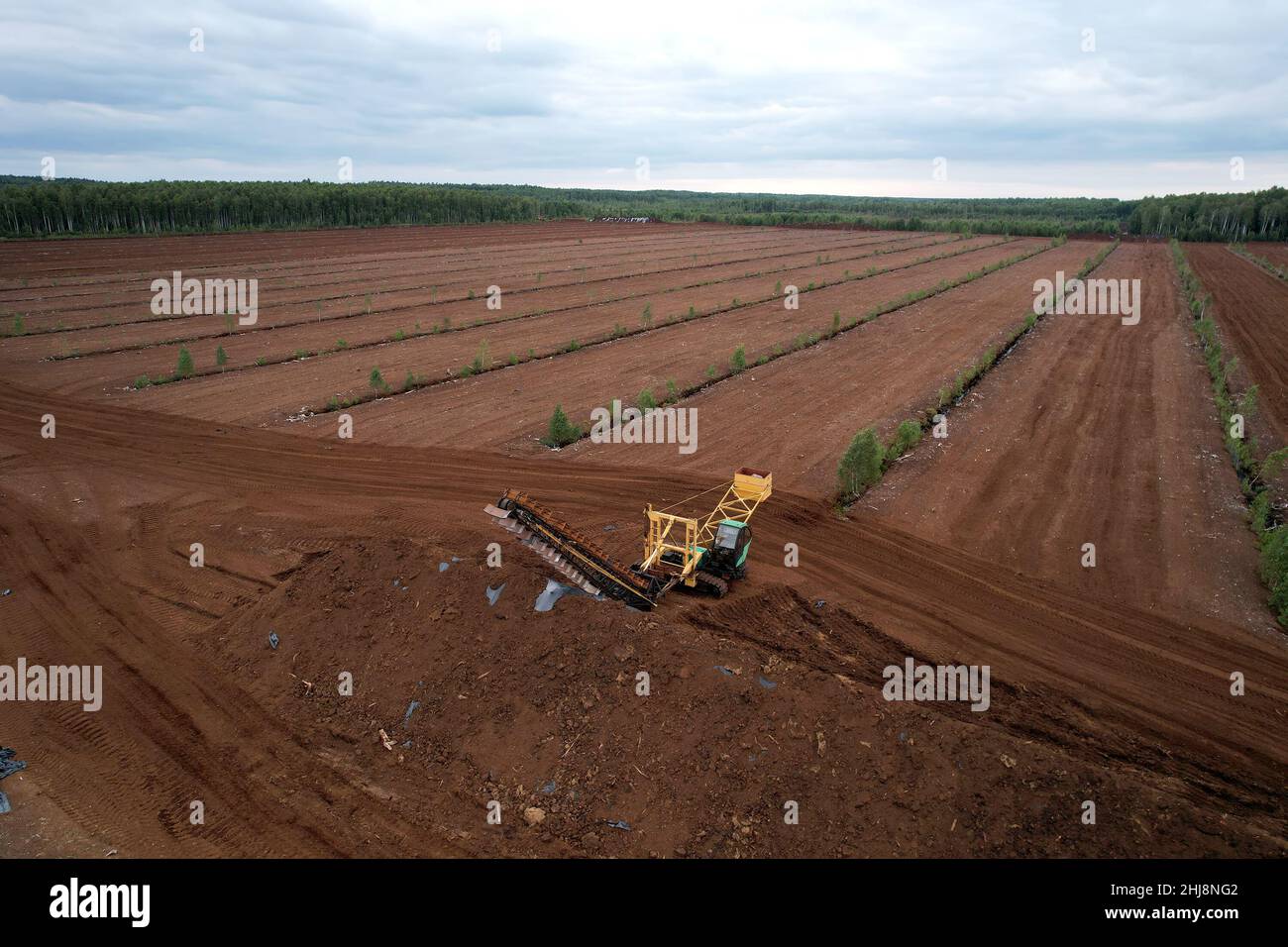 Peat harvesting field. Peat mining machine at peatland Harvester on ...