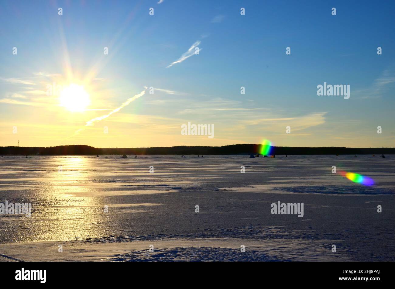 Two fishermen on a frozen lake catch fish in a hole of ice on the ...