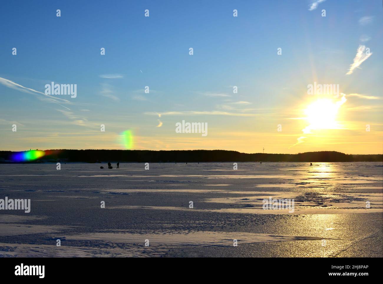 Two fishermen on a frozen lake catch fish in a hole of ice on the ...
