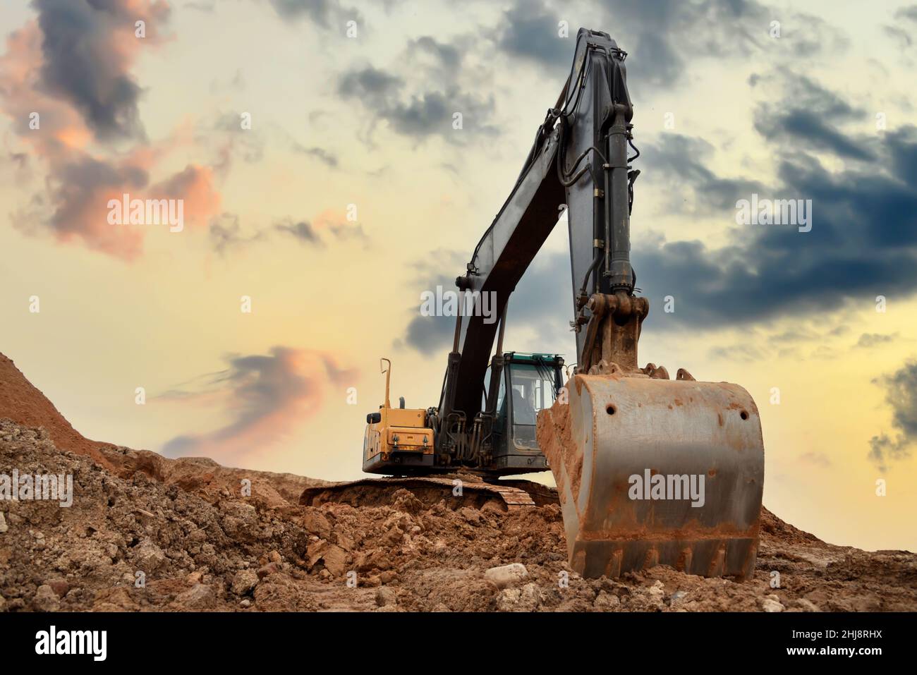 Excavator on earthmoving in open pit mining on sunset background ...