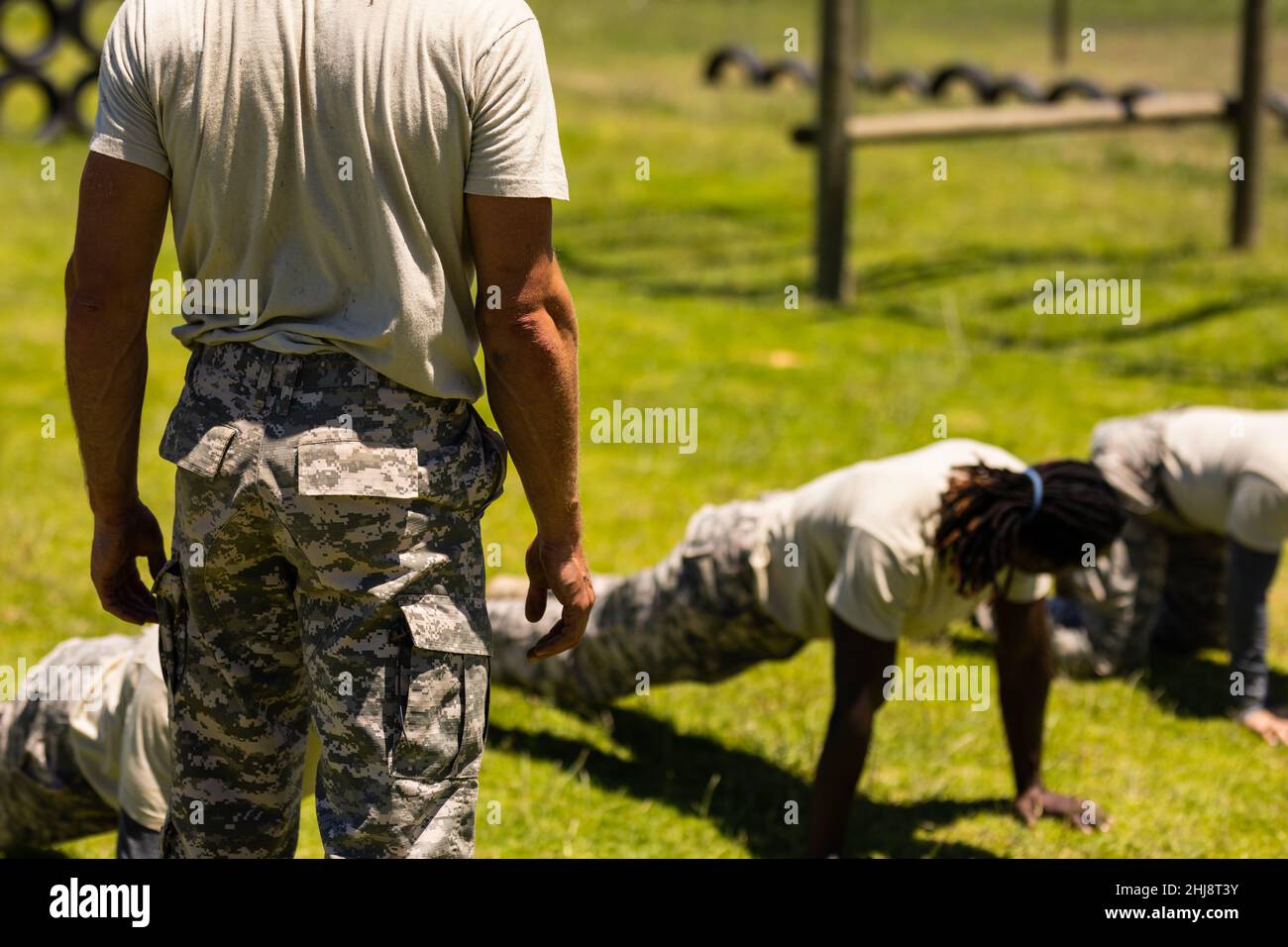 Mid section of male instructor standing while group of soldiers ...