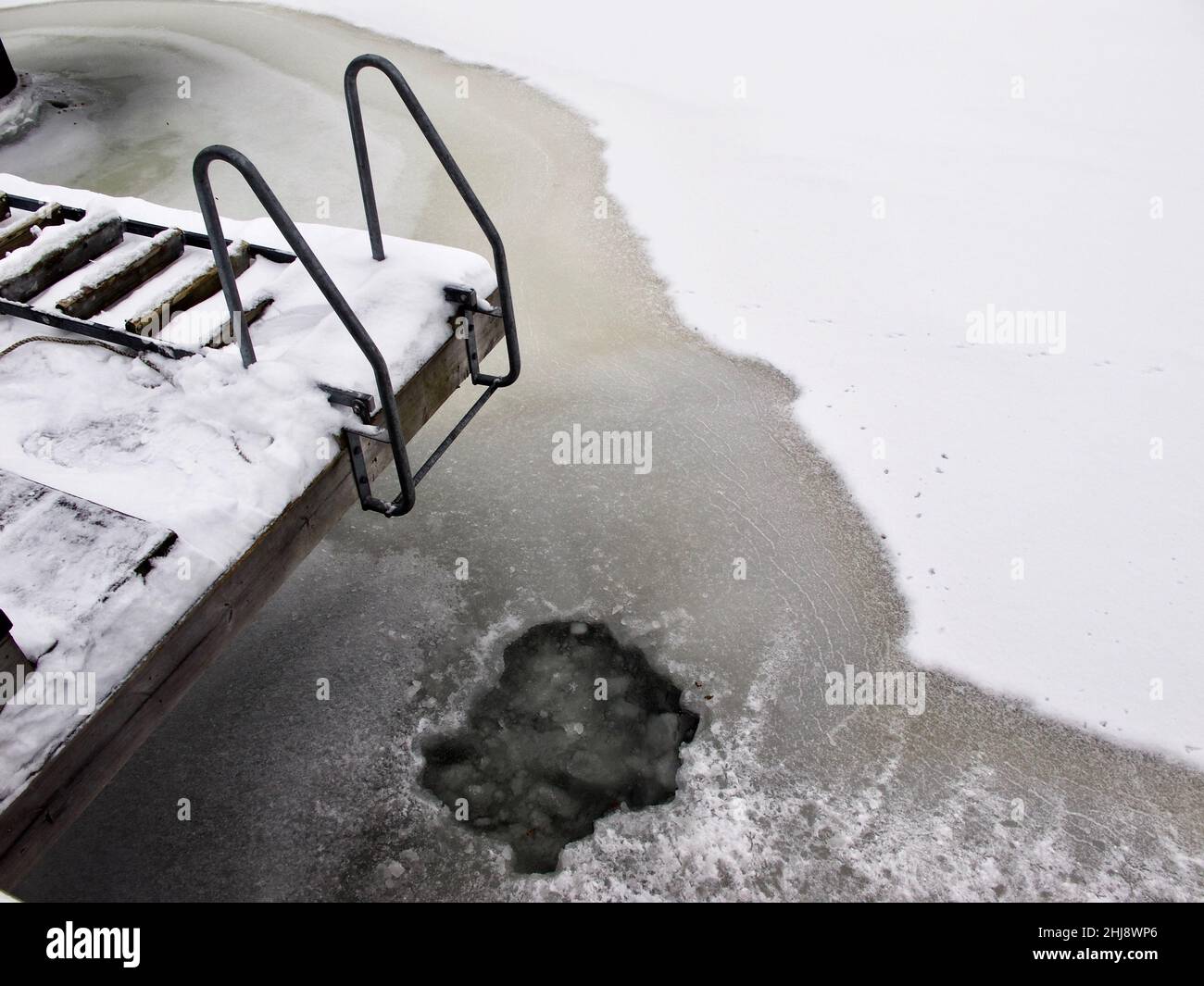 Bridge with ladder in winter with frozen sea and an open hole in the ...