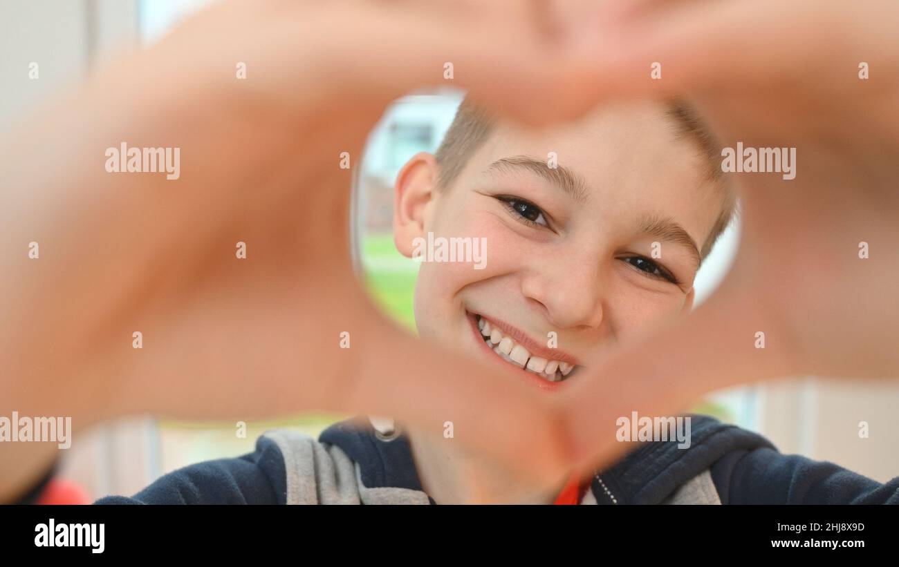Smiling teen boy showing heart shape with his fingers Stock Photo - Alamy