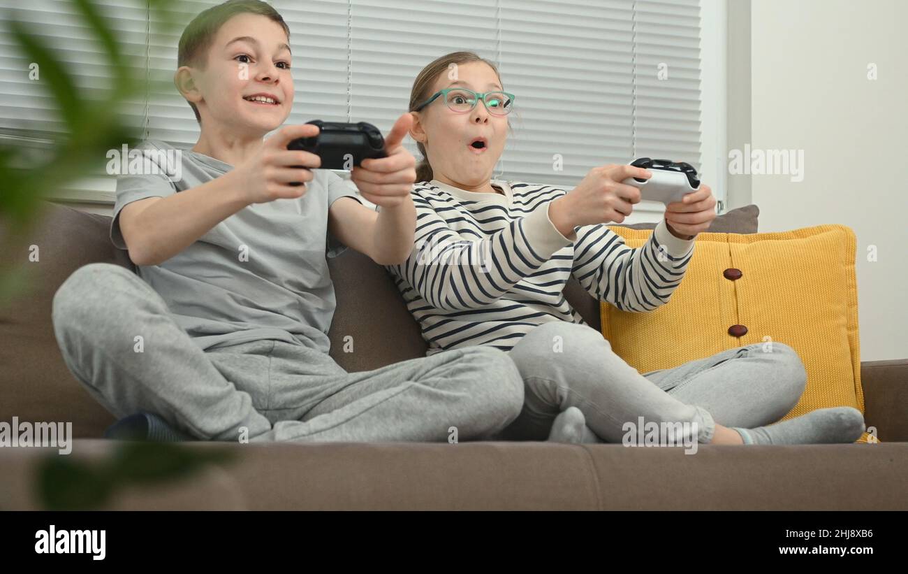 Excited brother and sister playing video game on a couch Stock Photo ...