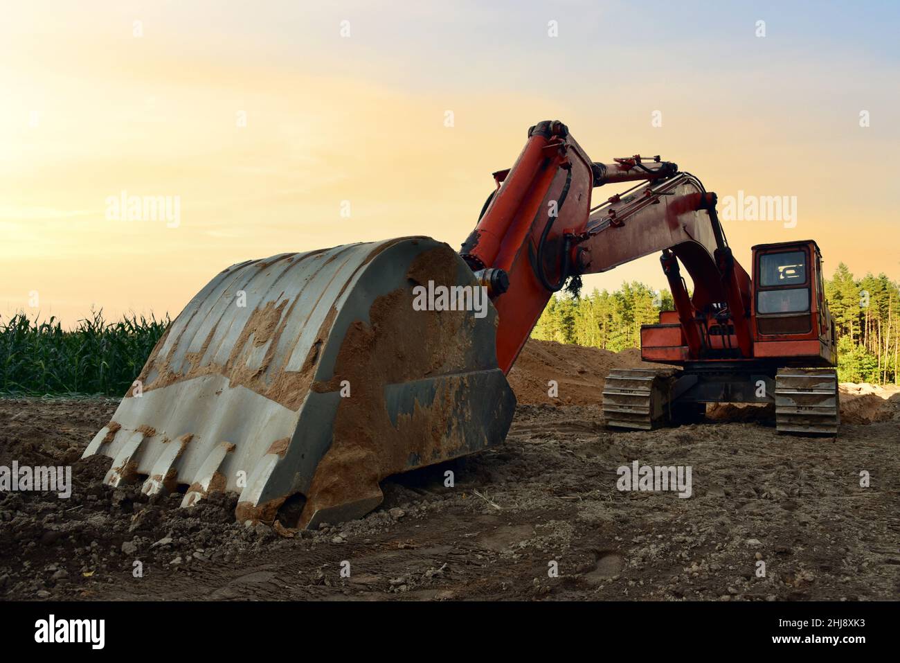 Excavator dig trench on sunset background. Backgoe on earthwork ...