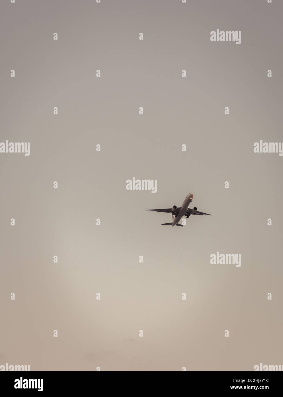 A vertical shot of a airplane flying in gray sky Stock Photo - Alamy