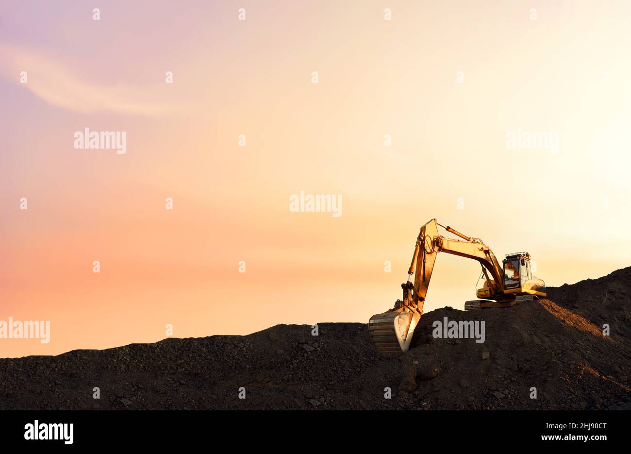 Excavator on earthmoving in open pit mining on sunset background ...