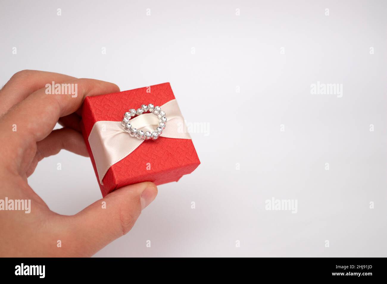 Red gift box in hand on white background Stock Photo - Alamy