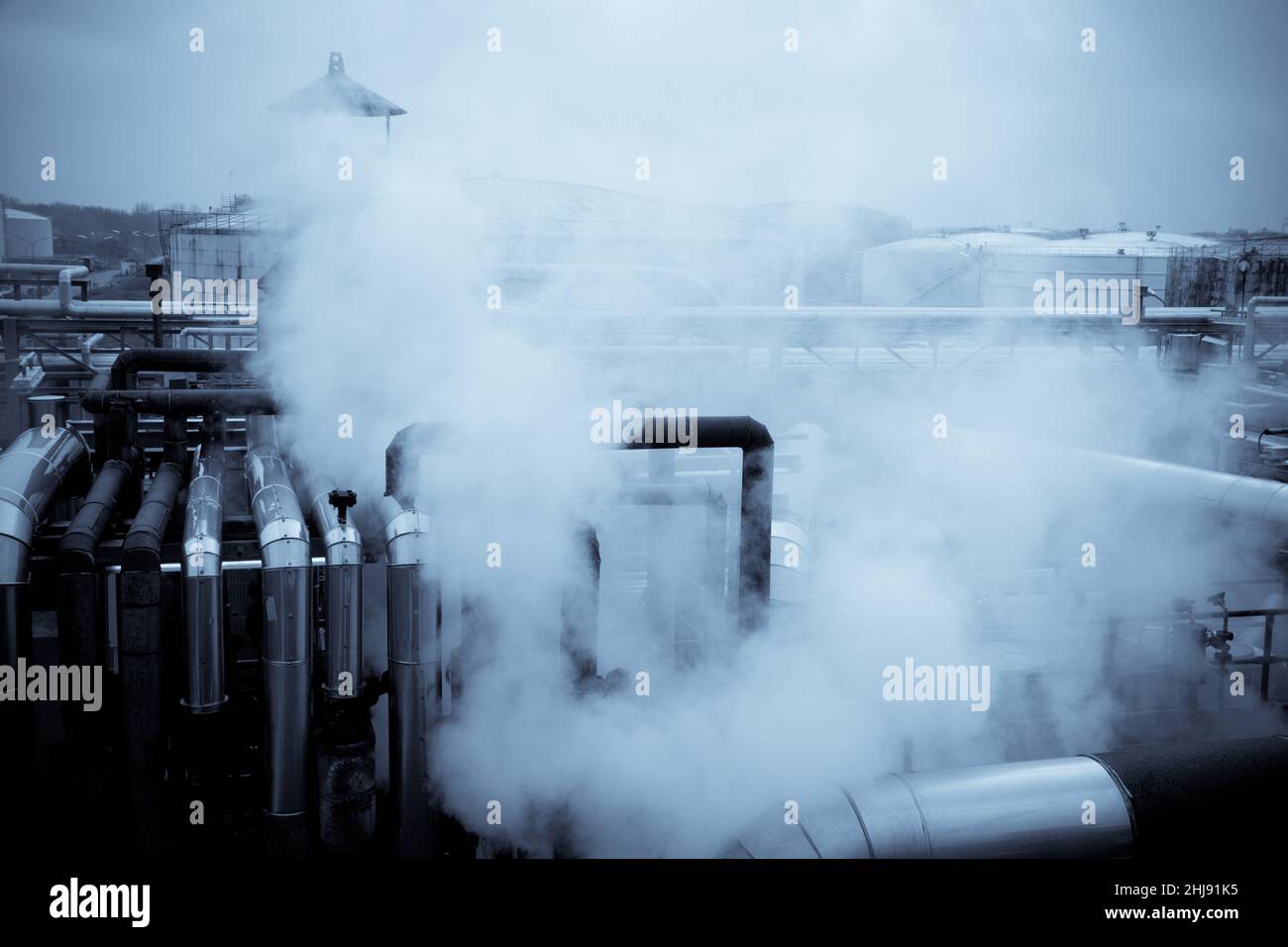 Piping of a chemical plant, partly covered in steam clouds with some ...