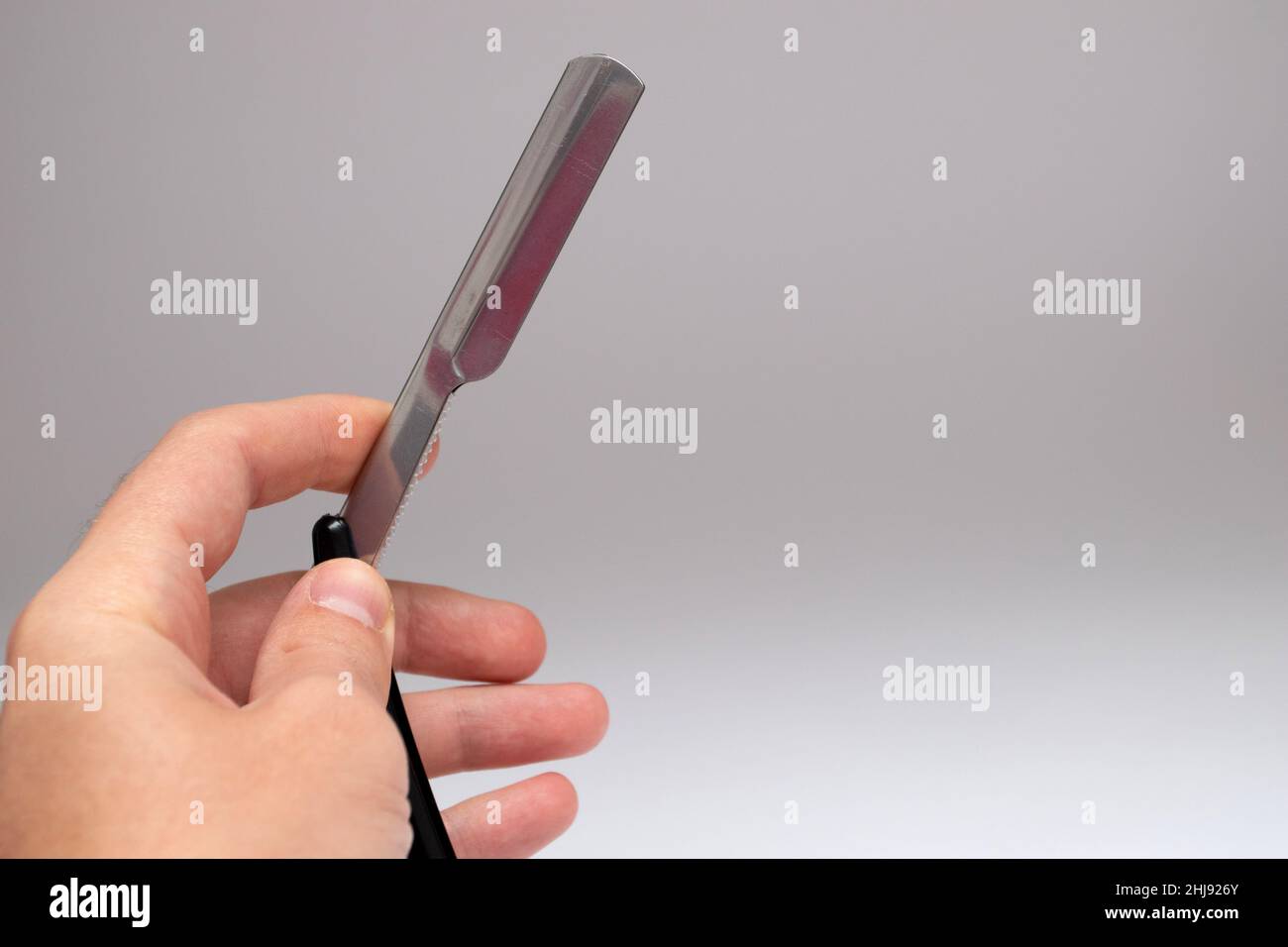 Hand holding a straight razor on a white background Stock Photo - Alamy