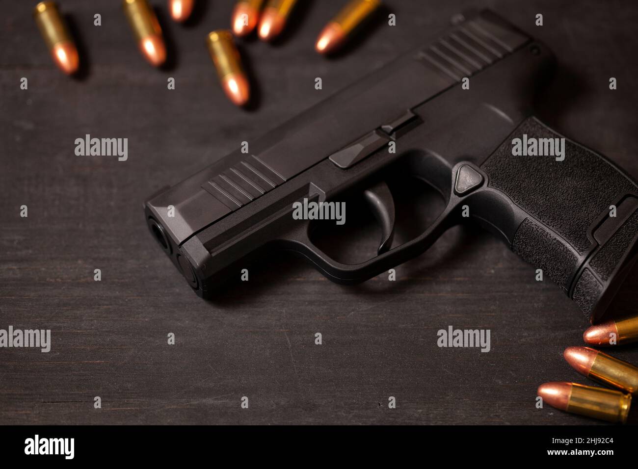Selective focus view of black pistol and bullets on black wood ...