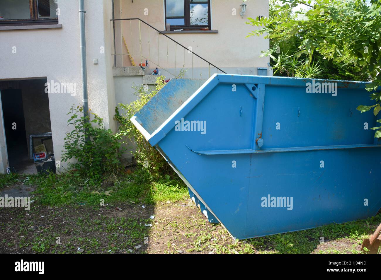 A large empty garbage container stands in a yard at an old house Stock ...