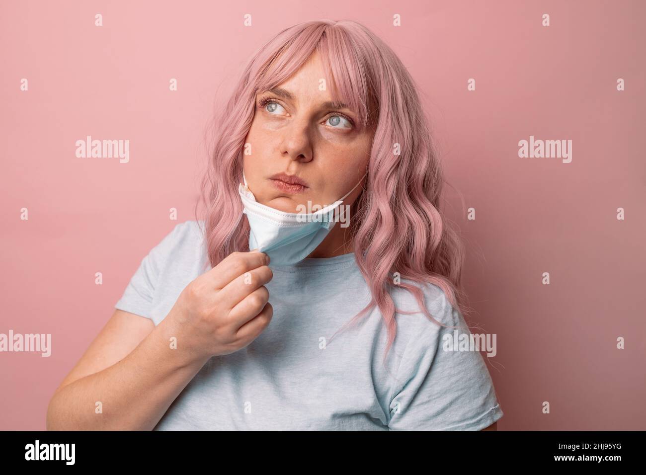 Mask off. Displeased young 30s girl takes off protective mask from her ...