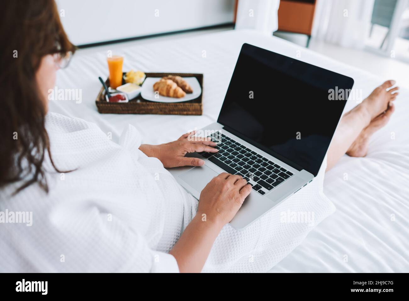 Woman lying on bed with laptop Stock Photo - Alamy