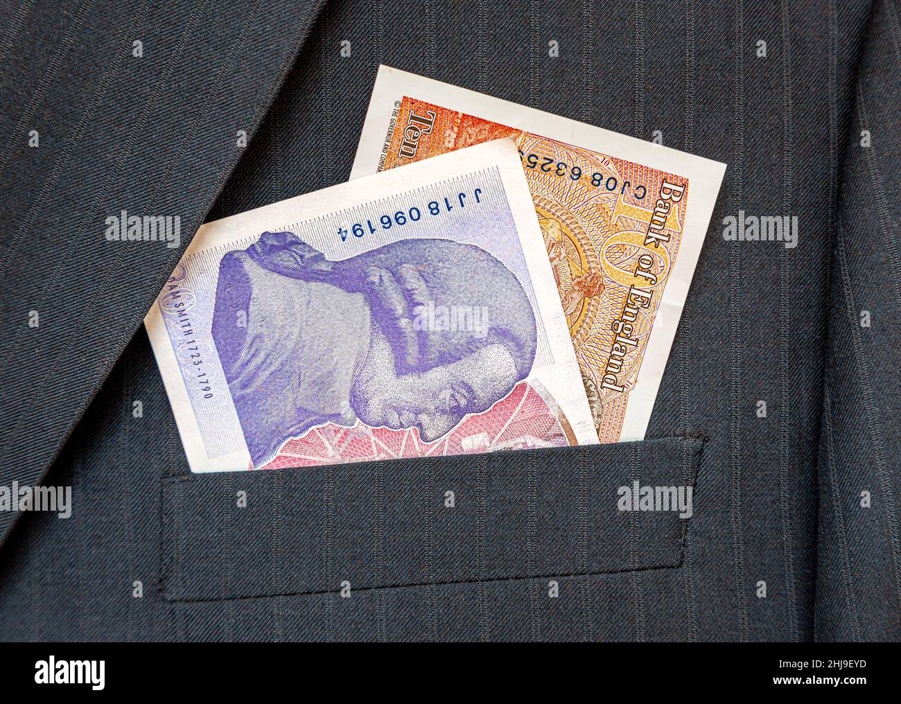 Banknotes of British pounds sticking out out of the businessman suit ...