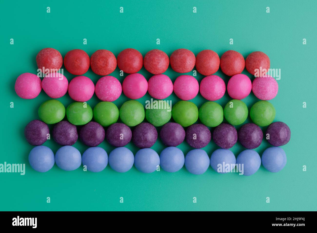 Rows of sweet, colorful, round candies, each in its own color on a ...