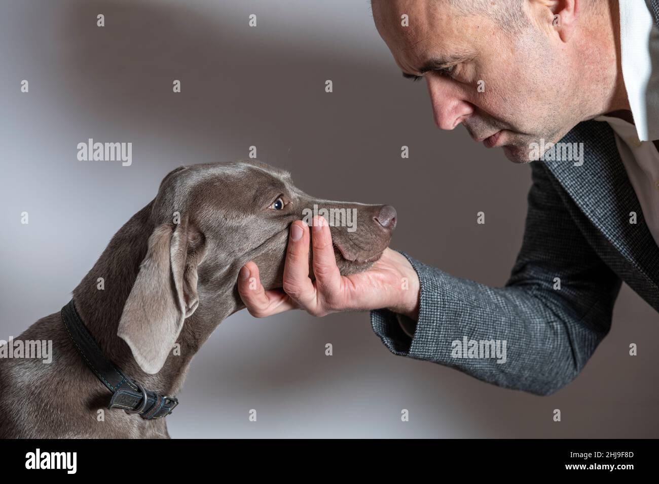 A man looking at his dog's eyes and holding his face with his hand ...